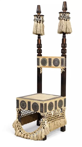 Fringed throne chair dominated by two carved wooden columns adorned ...