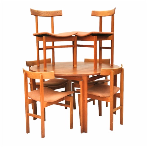 a teak dining table, with a circular table top raised over offset legs ...