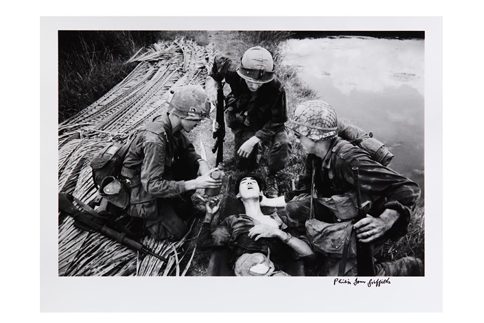 WOUNDED VIET CONG, 1968, American soldier offering water to a severely ...