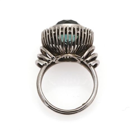 A zircon- and diamond ring set with a circular-cut zircon encircled by ...
